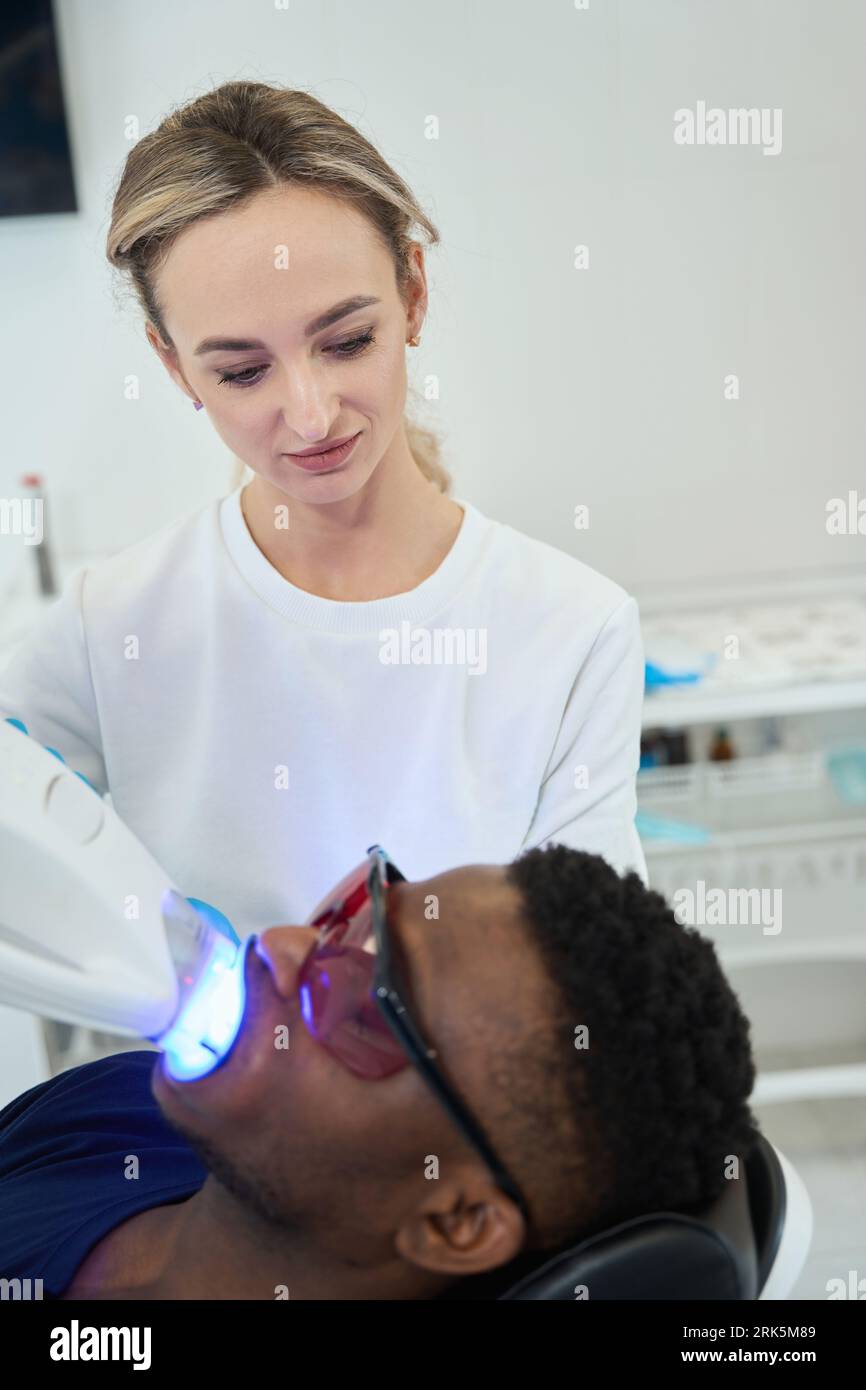 Doctor performing teeth whitening procedure on male Stock Photo - Alamy