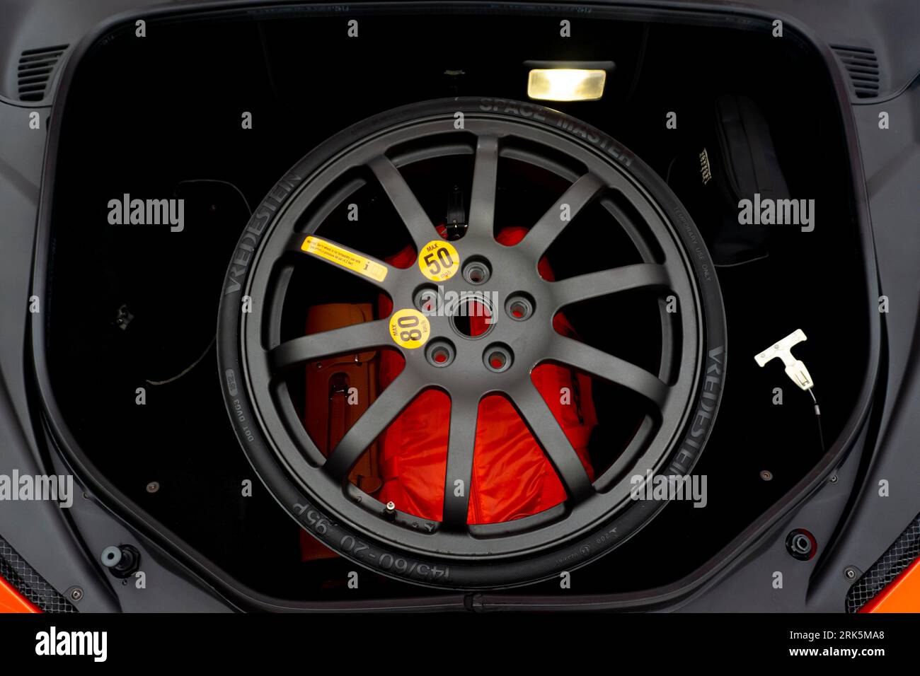 A red Ferrari with an open door is seen with a large wheel in its ...