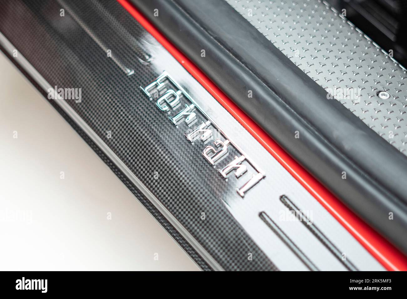 A Ferrari carbon fiber door sill with brand's name inscription, red car ...