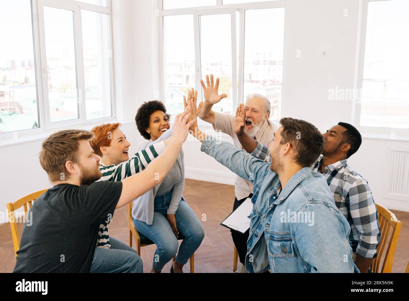 Wide shot of multicultural and different ages people sitting in circle ...