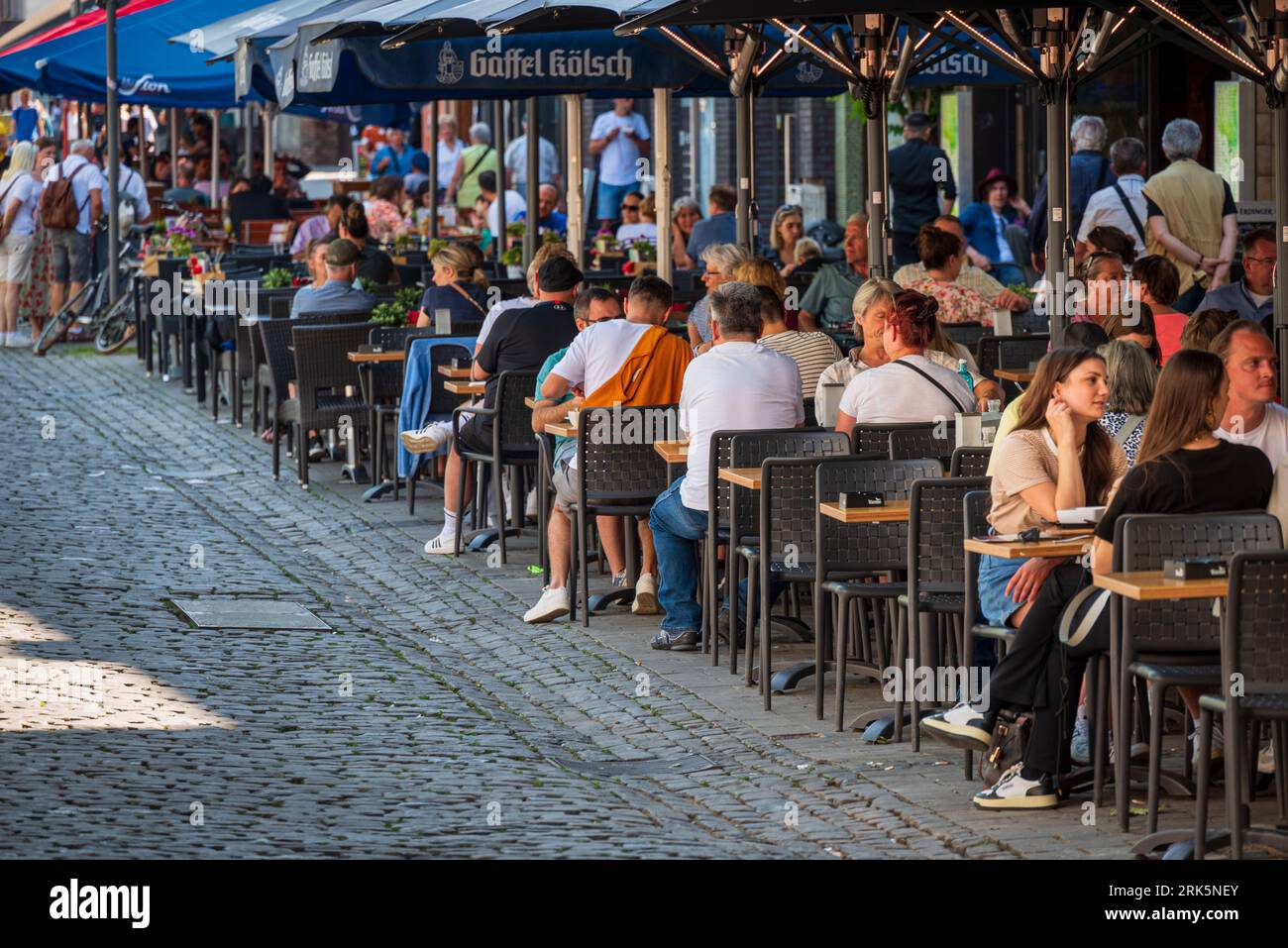 The people sitting in an outdoor cafe in the old town of Cologne ...