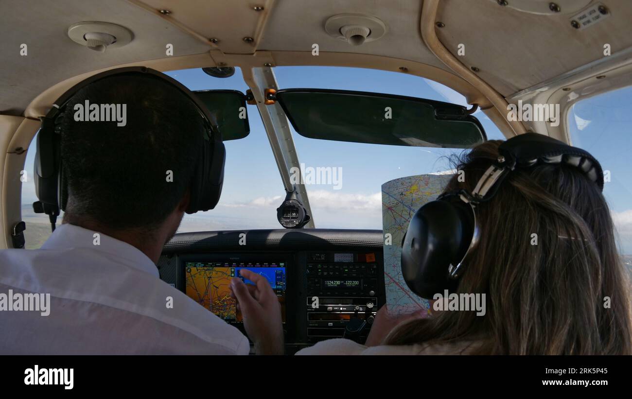 A couple inside the cockpit of an airplane with a map checking the ...