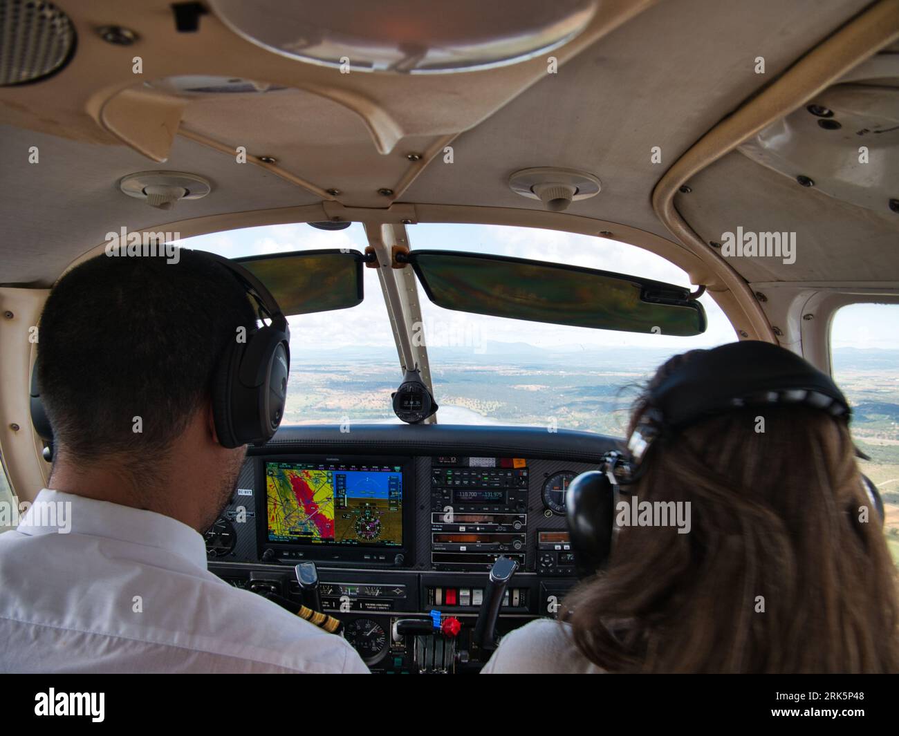 A couple inside the cockpit of an airplane with a map checking the ...