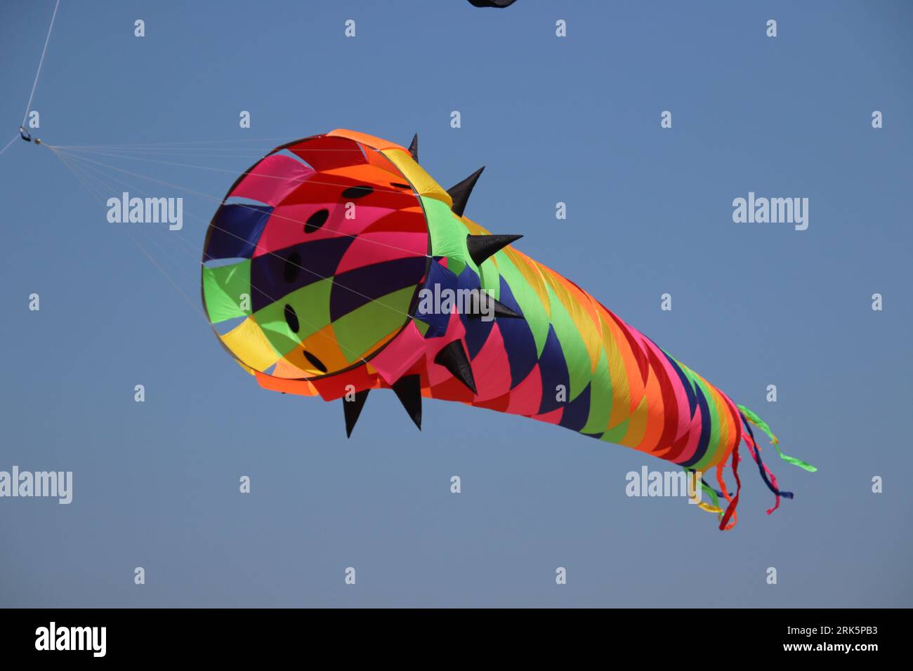 A vibrant multi-colored kite in the shape of an extraterrestrial being ...
