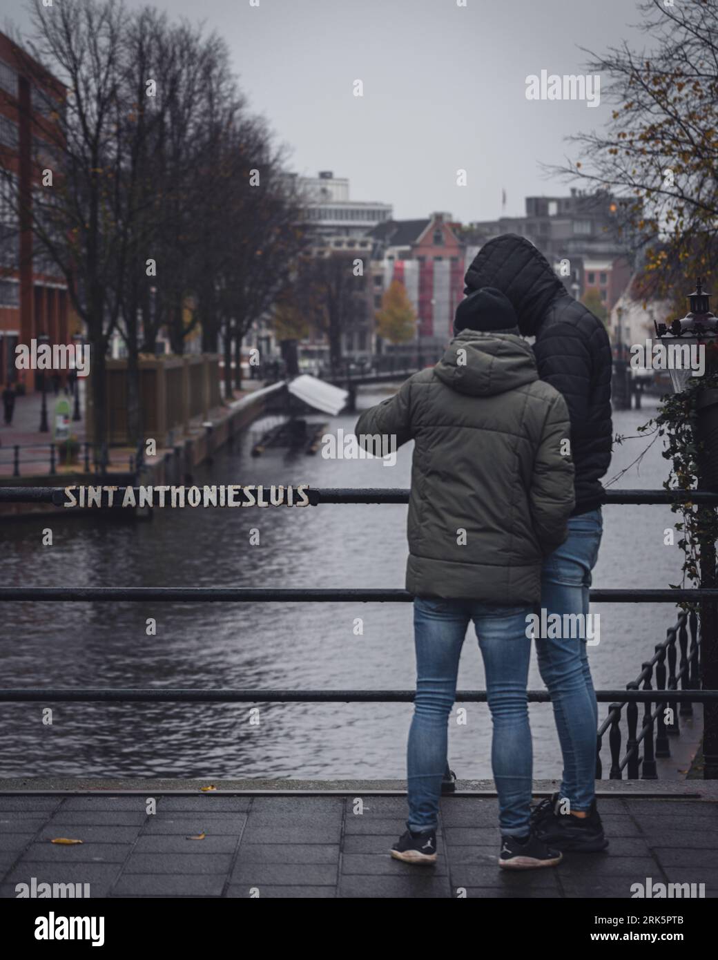 Two people look at directions on a bridge next to a canal in Amsterdam ...