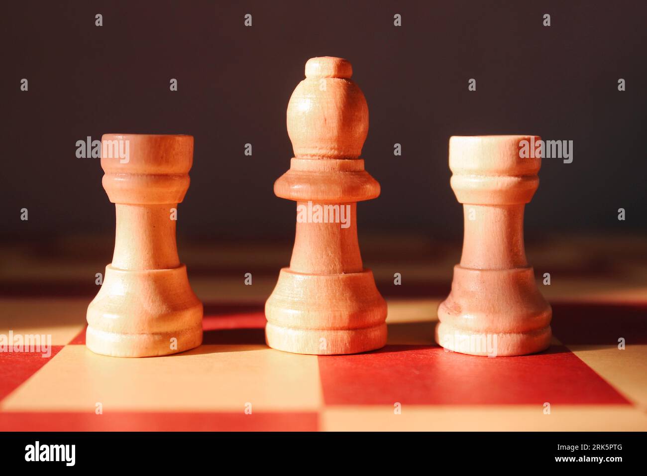 Three wooden chess pieces in different colors lie on a flat surface ...
