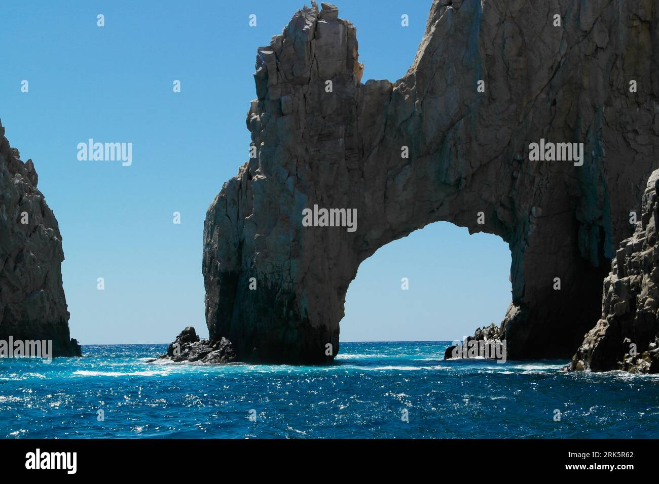 A small group of people are seen sailing in a boat in an open body of ...