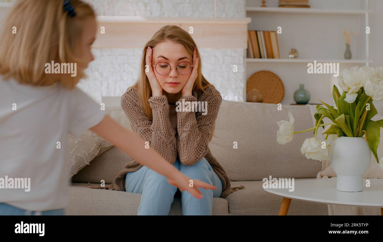 Tired upset Caucasian mother sitting on sofa at home sad frustrated ...