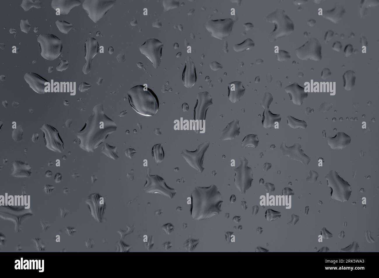 Close-up shot of a window covered in raindrops, with a blurred view of ...