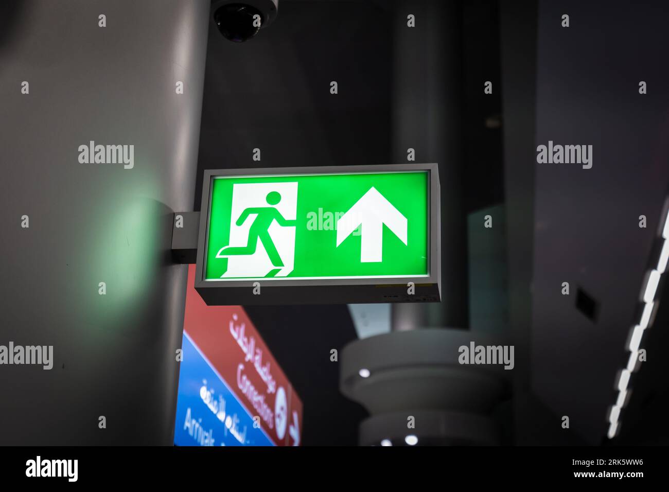 A glowing green exit sign illuminated against a black background ...