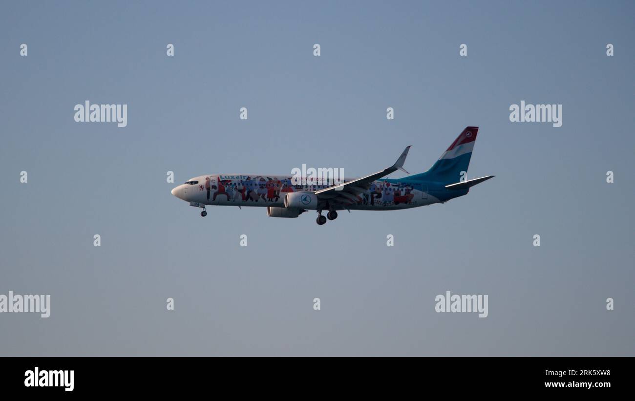 An airplane flying in the sky, with a graffiti design on the tail ...