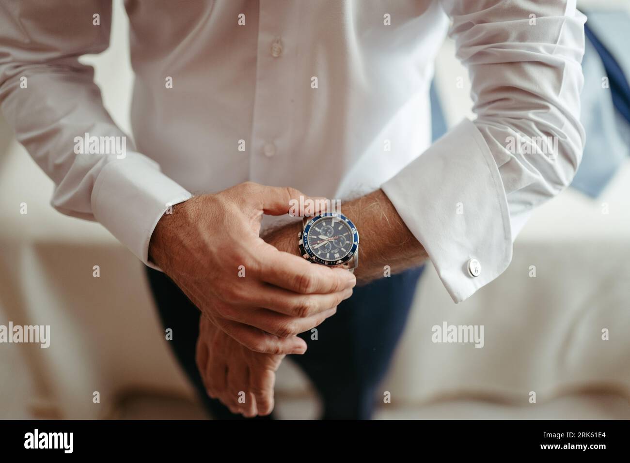 A young, Caucasian man wearing a stylish wristwatch looks at the time ...