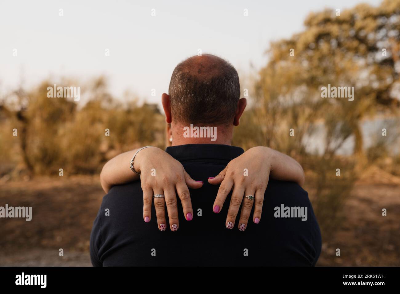 Two people standing side by side looking away from the camera, with ...