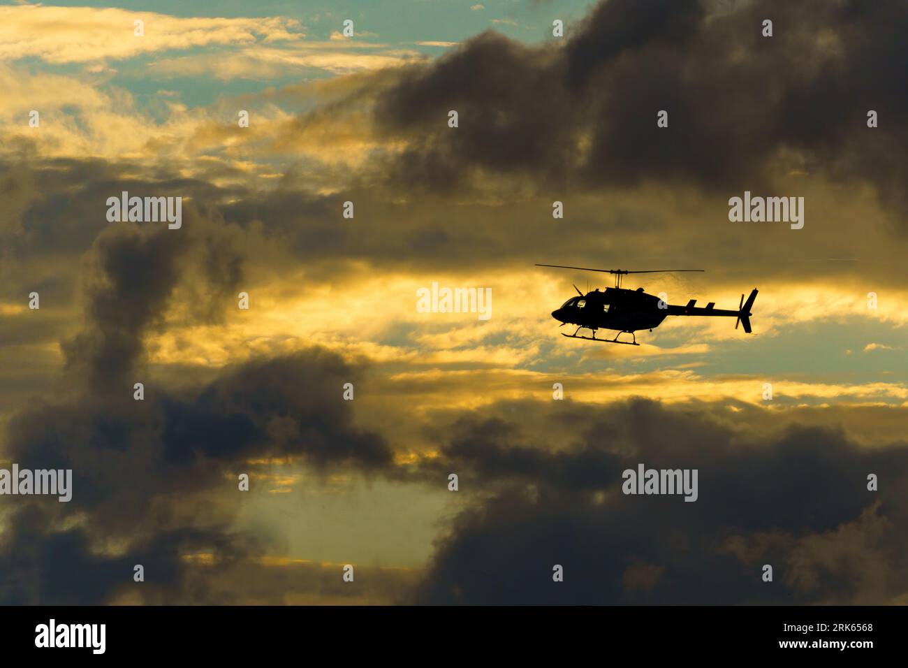 A military helicopter is pictured soaring through a cloudy sky at dusk ...