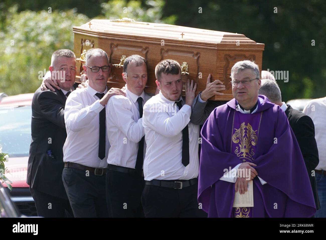 Father Gerry Boyle (right) walks in front of the coffin of Brendan Wall ...