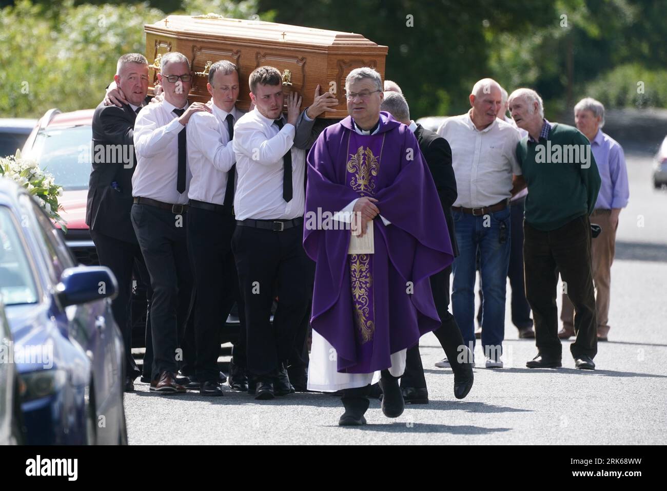 Father Gerry Boyle (left) walks in front of the coffin of Brendan Wall ...