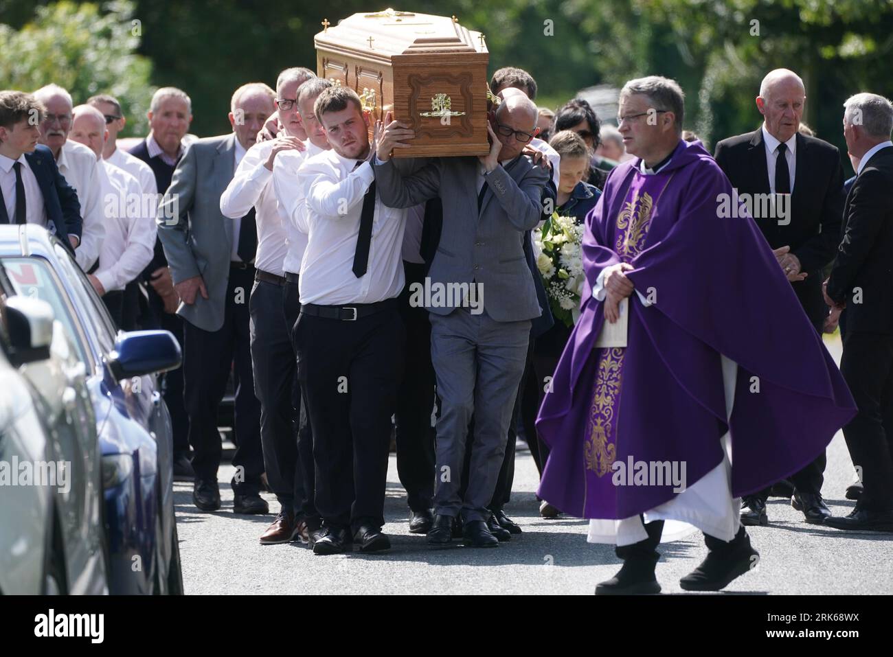 Father Gerry Boyle walks in front of the coffin of Brendan Wall as it ...