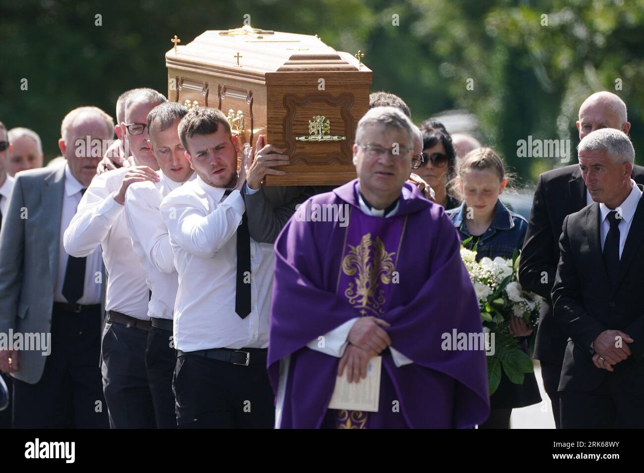 Father Gerry Boyle walks in front of the coffin of Brendan Wall as it ...