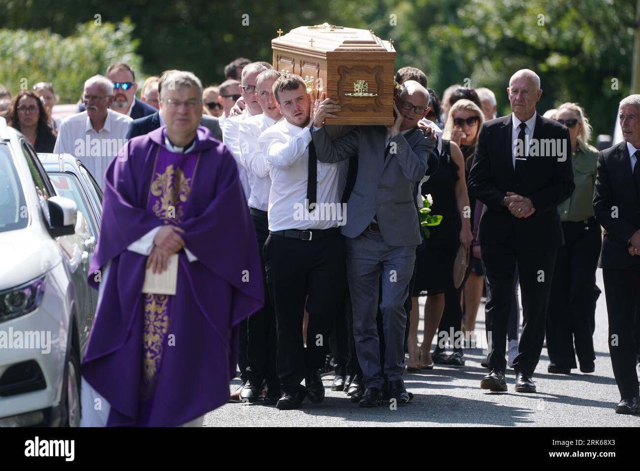 Father Gerry Boyle (left) walks in front of the coffin of Brendan Wall ...