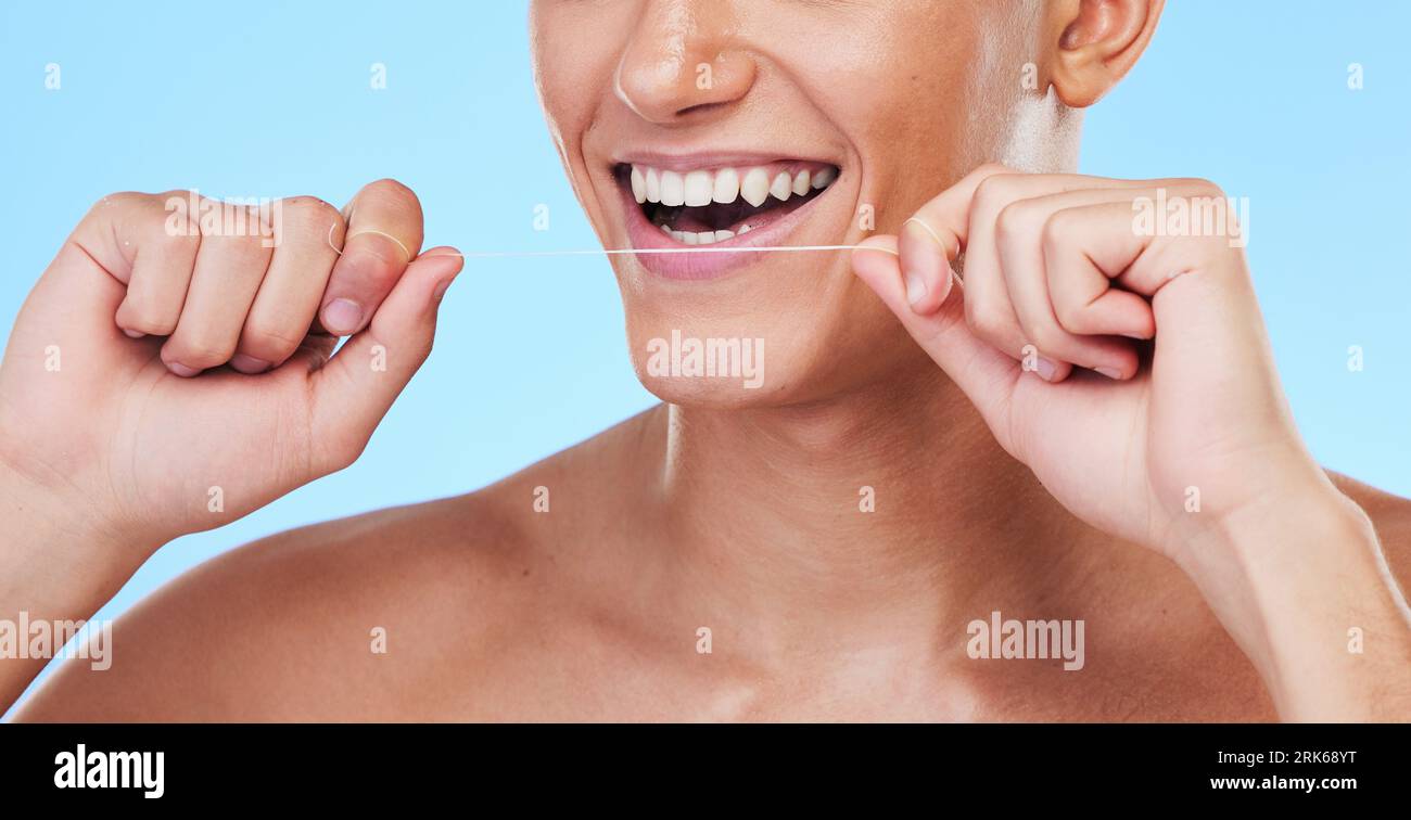 Happy man, dental floss and cleaning teeth in oral hygiene or grooming against a blue studio ...
