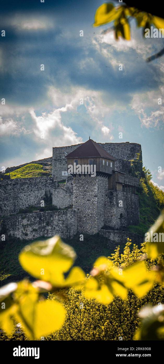 A majestic castle stands atop a hill, with a cloudy sky looming ...