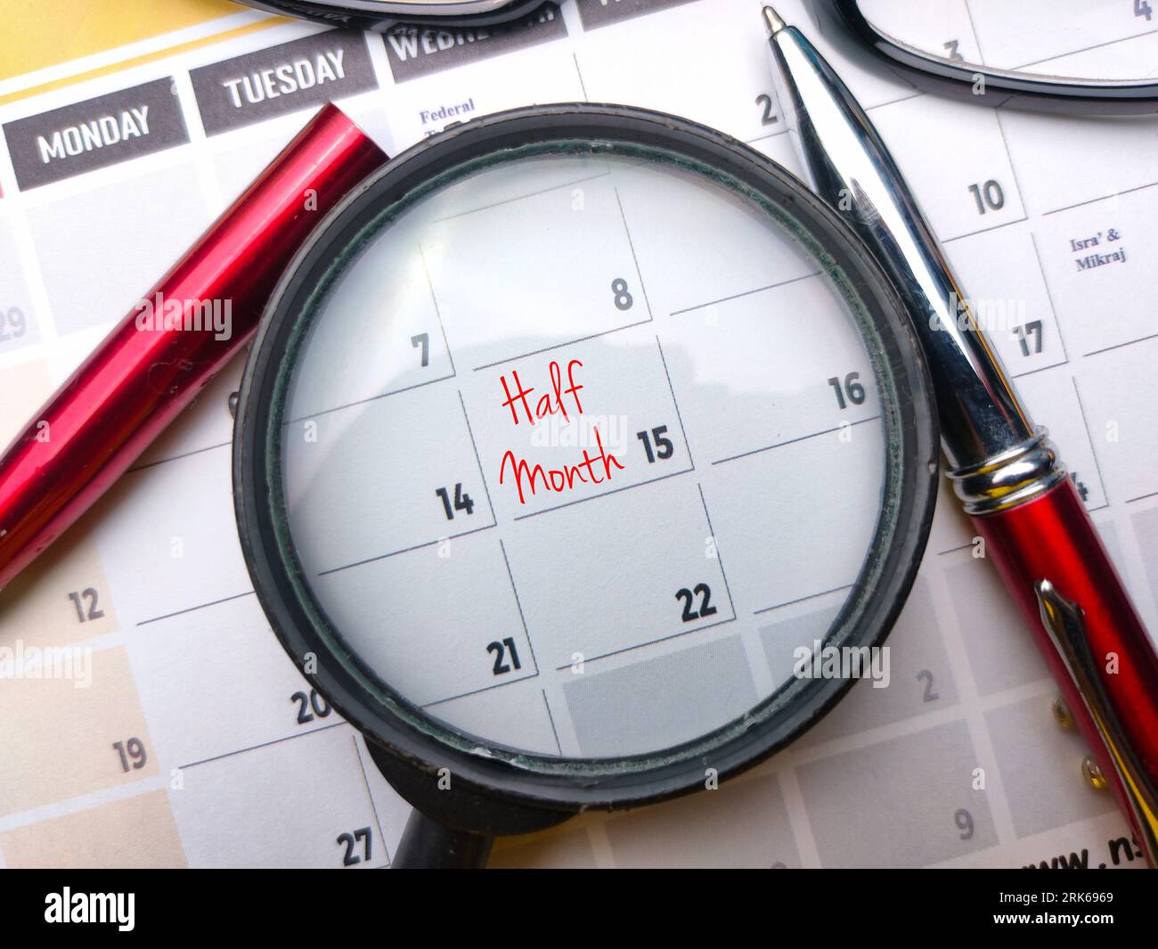 A magnifying glass placed on top of a printed calendar, with a blurred ...