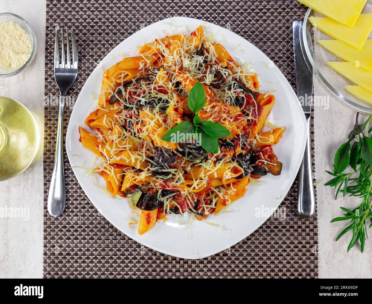 A plate of cooked pasta with olives and a glass of wine, ready to be ...