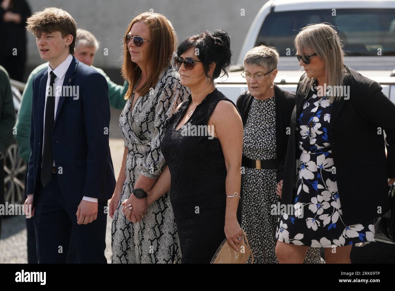 Family members and mourners look on as the coffin of Brendan Wall is ...