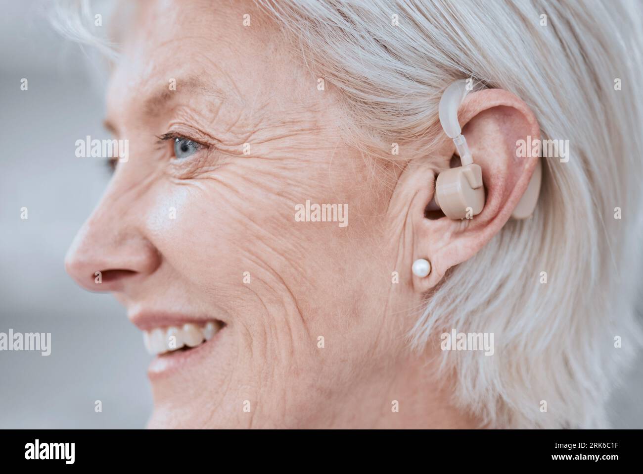 Senior woman, hearing aid and ear with smile, profile and audio for ...