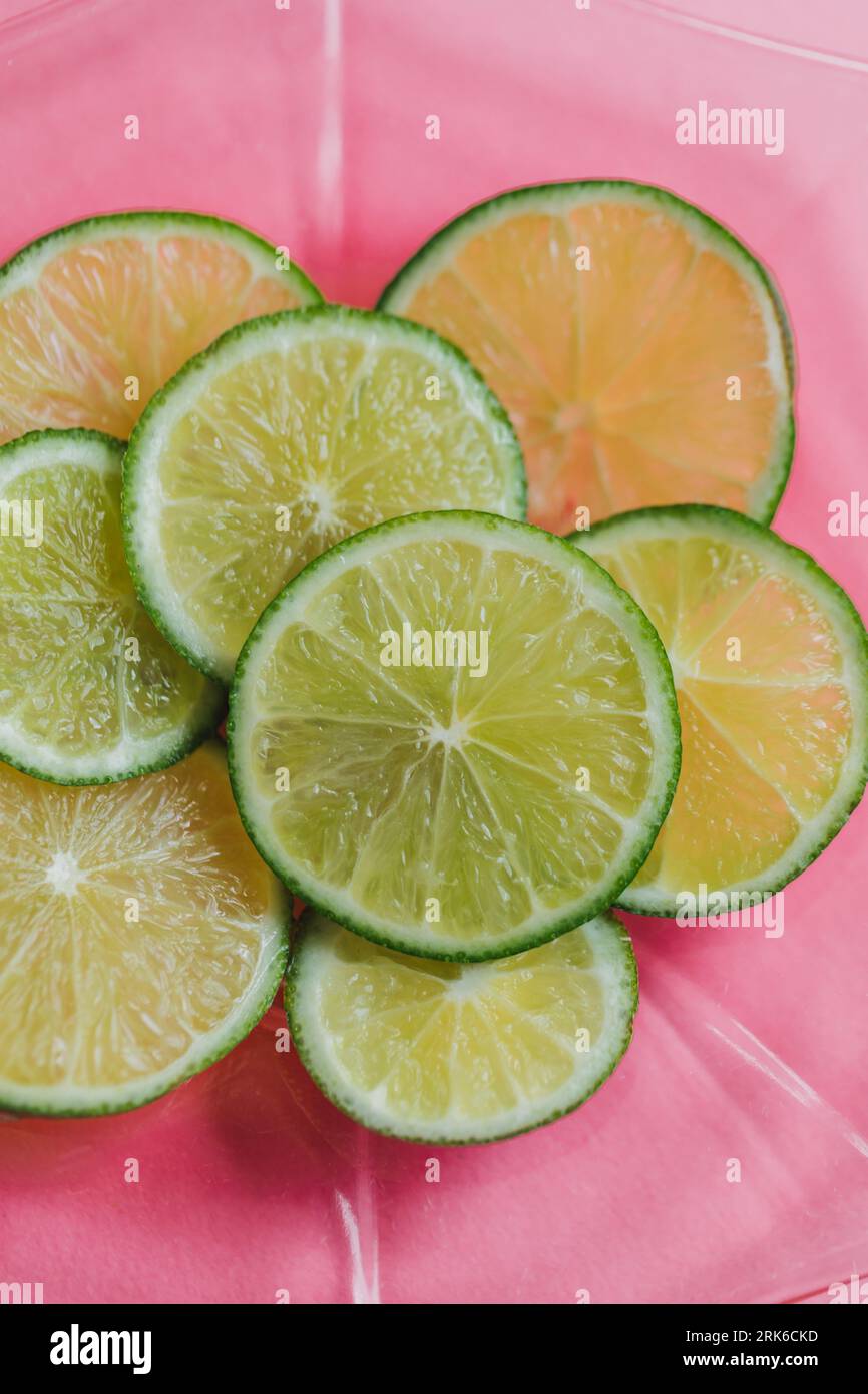 bright green sliced lime wheels on octagonal pink glass plate on pink ...
