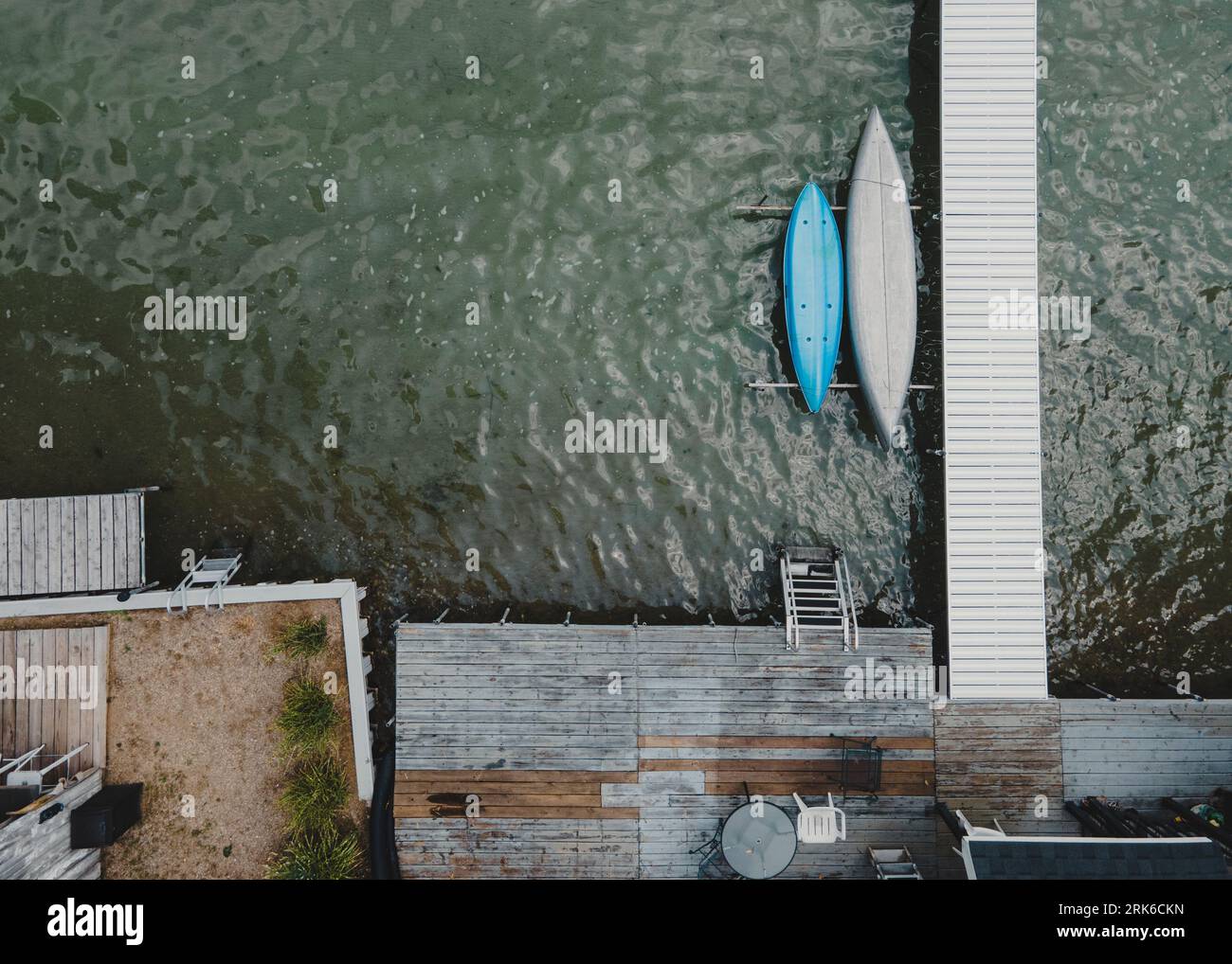 An aerial view of a wooden dock extending out into the water with two ...