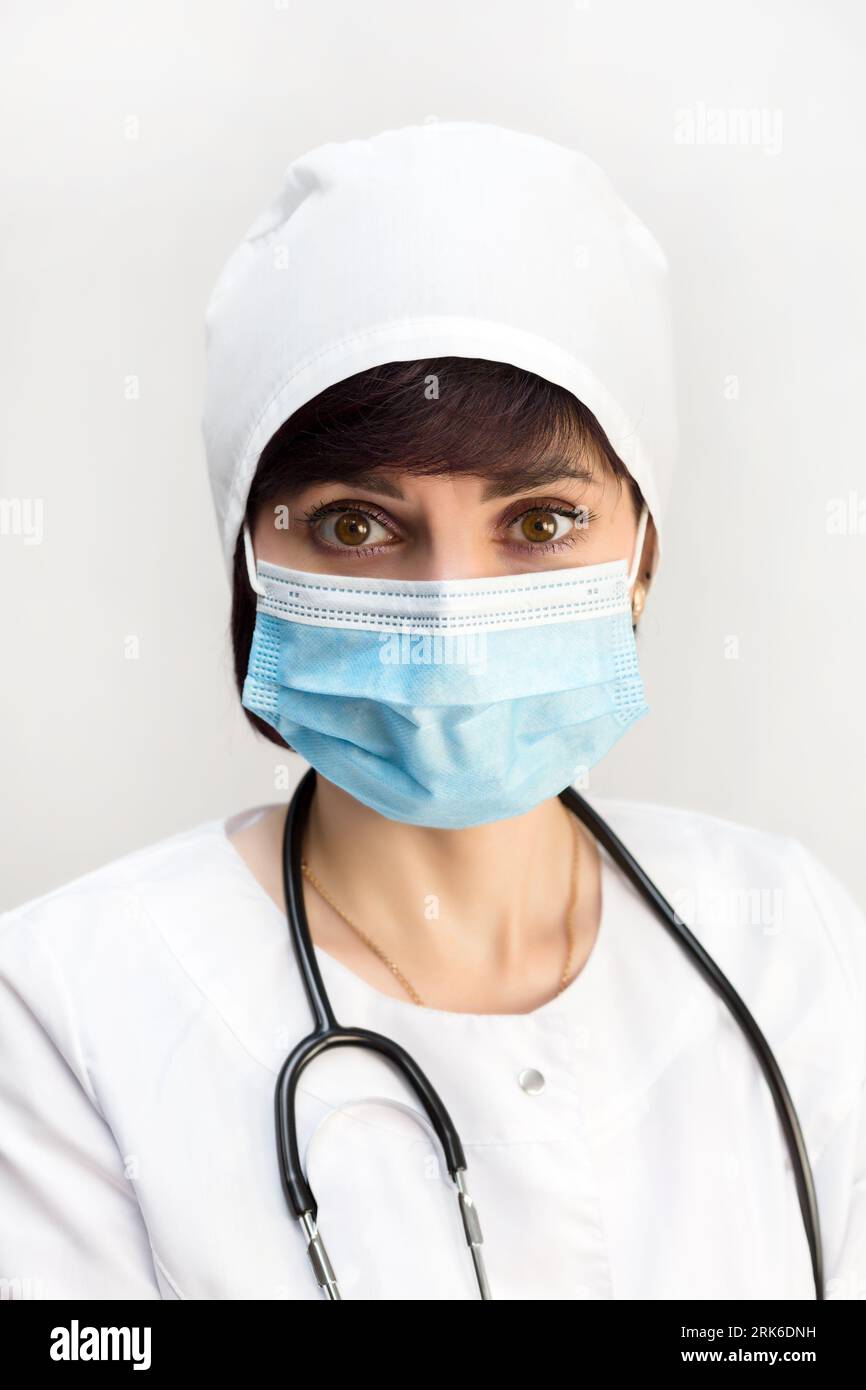 Face of a female doctor in a medical mask cap with brown eyes, close-up ...