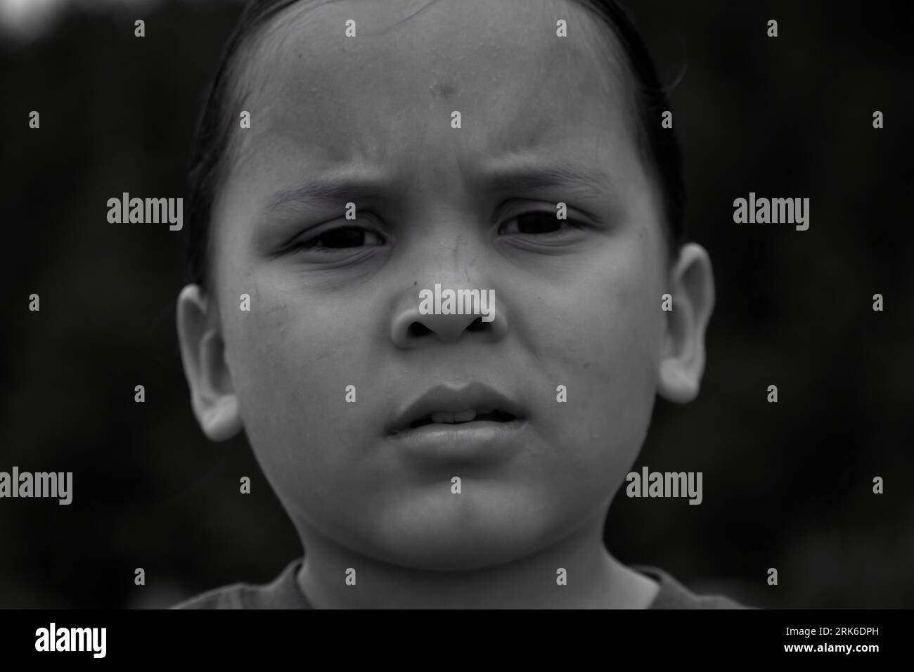 A grayscale portrait of a young Native American boy with a content ...