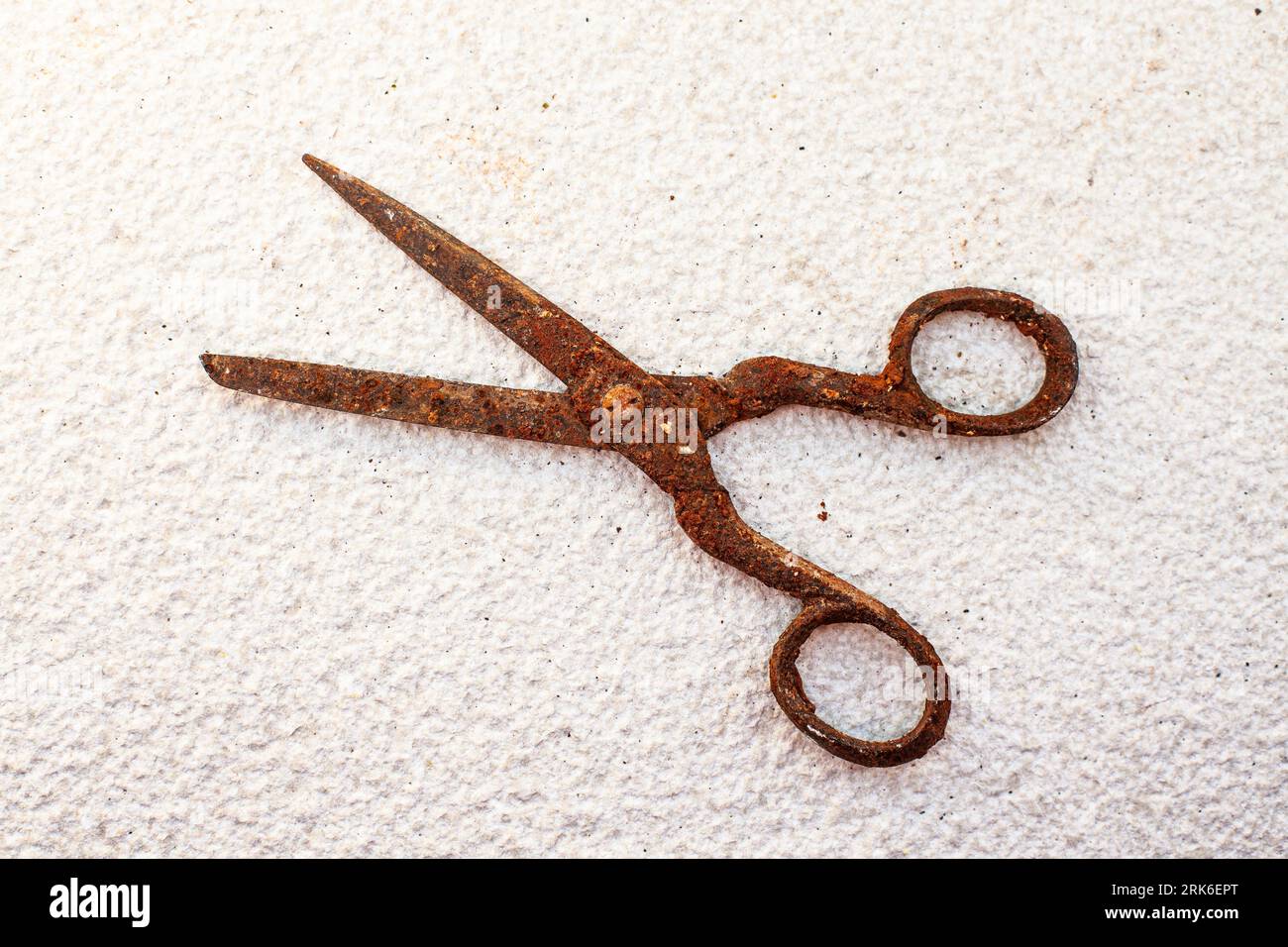 Old vintage scissors covered in rust on white stone background ...