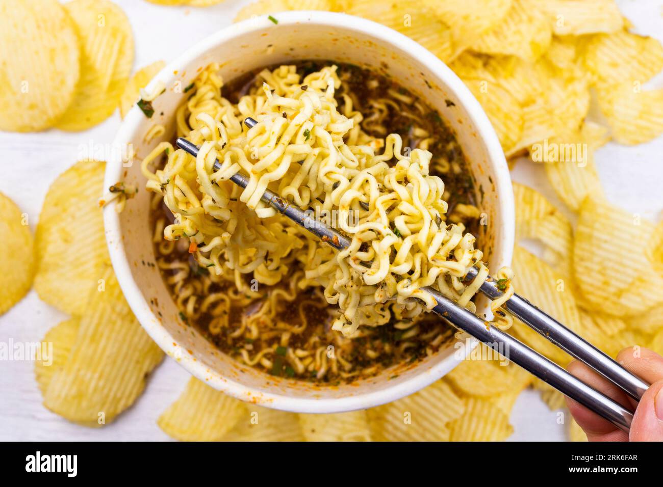 A top view of Chinese noodles with spices on a white table with chips ...