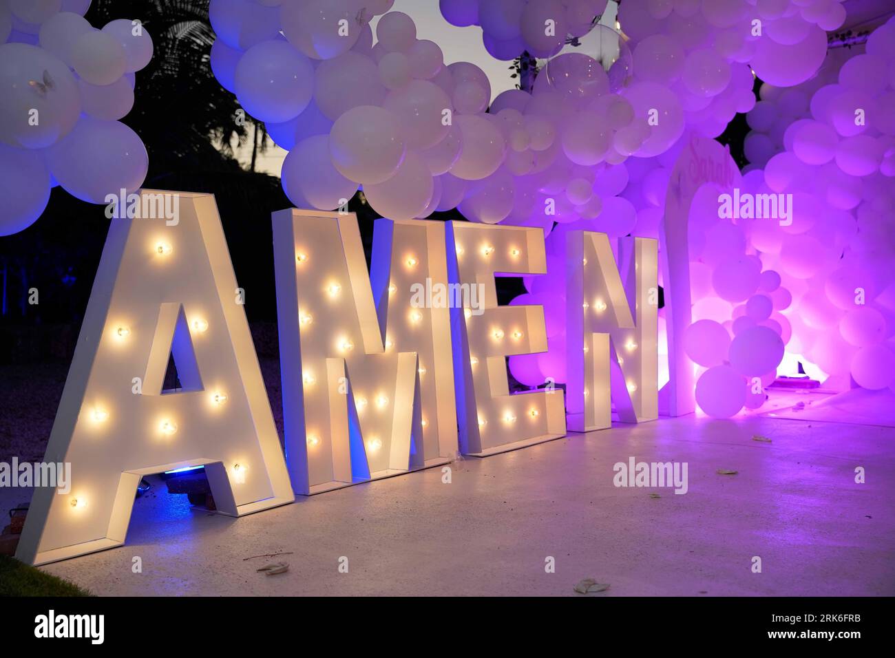 The decorative lights with the word 'Amen' and balloons in purple hues ...