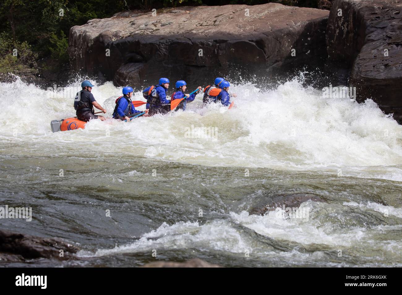 A group of people in a kayak navigating through the choppy waters of a ...