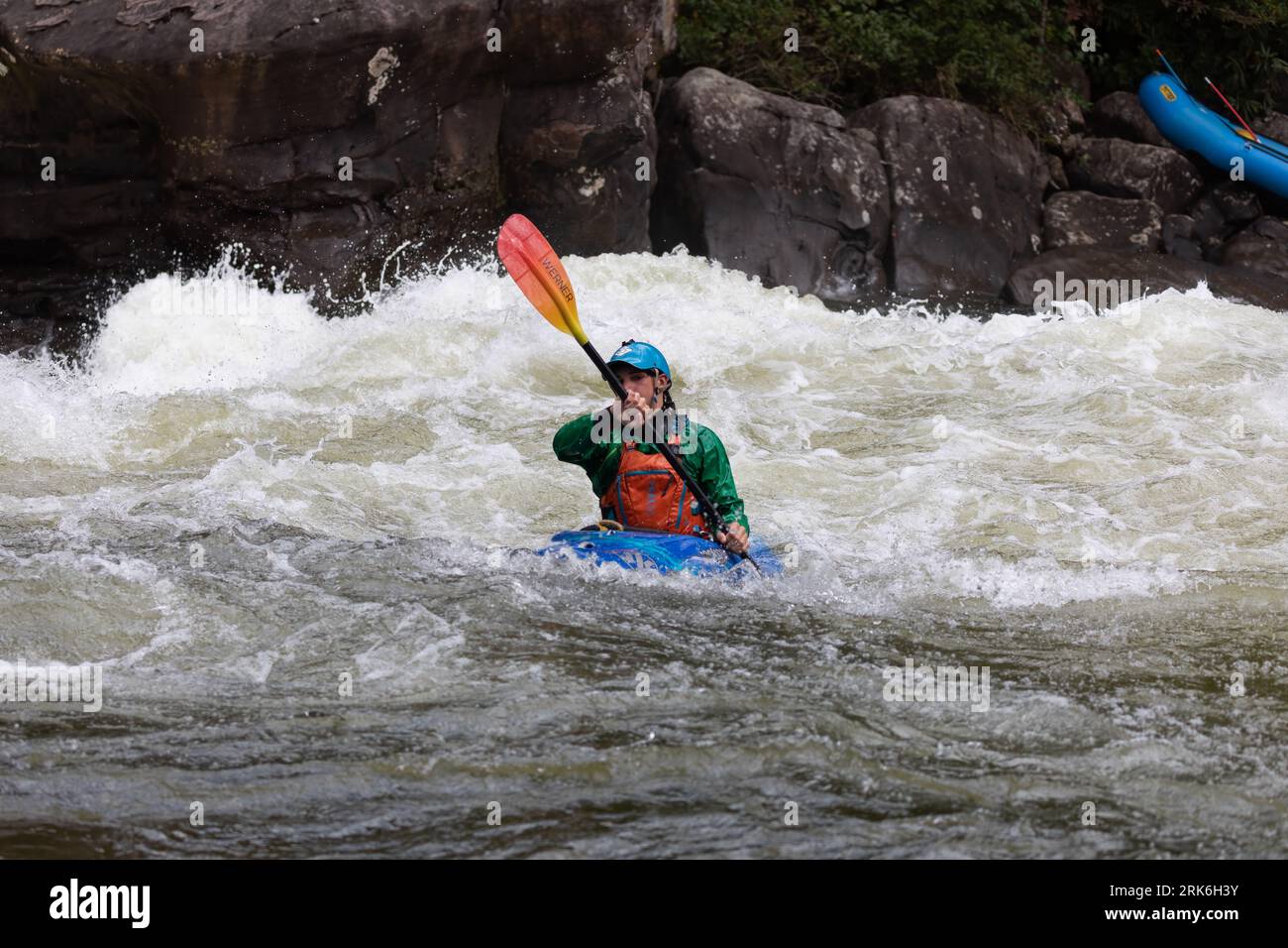 A person in a kayak navigating through the choppy waters of a river in ...