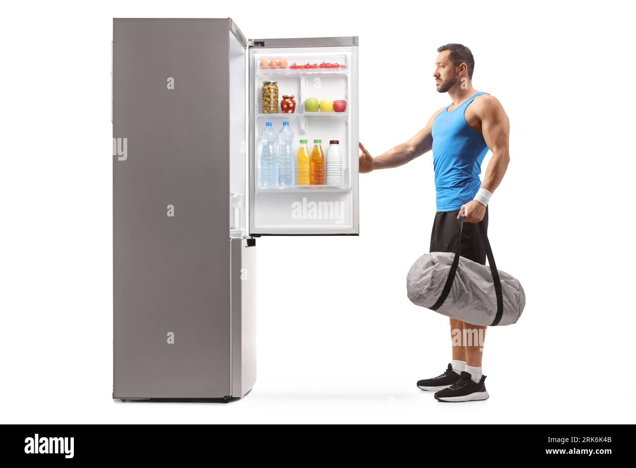 Male athlete holding a sports bag and opening a fridge isolated on ...