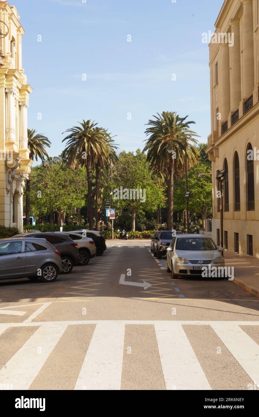 An array of parked cars are seen on a city street, near a stop sign ...