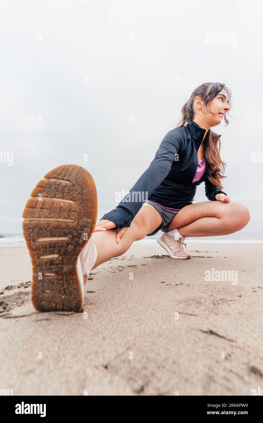 A young woman with a disabled hand performing a stretching exercise ...
