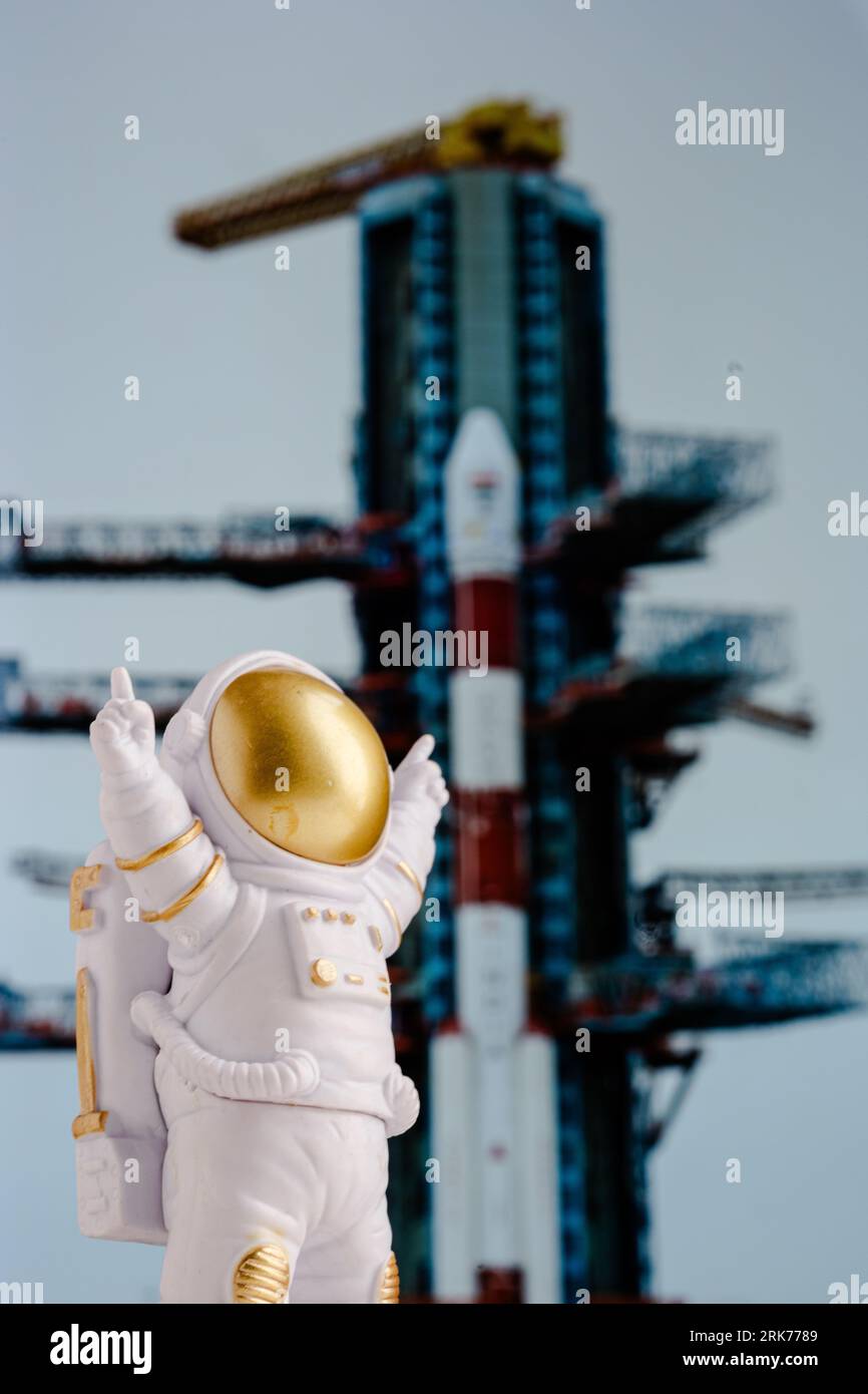 A toy astronaut figure stands against a backdrop of a rocket taking off ...