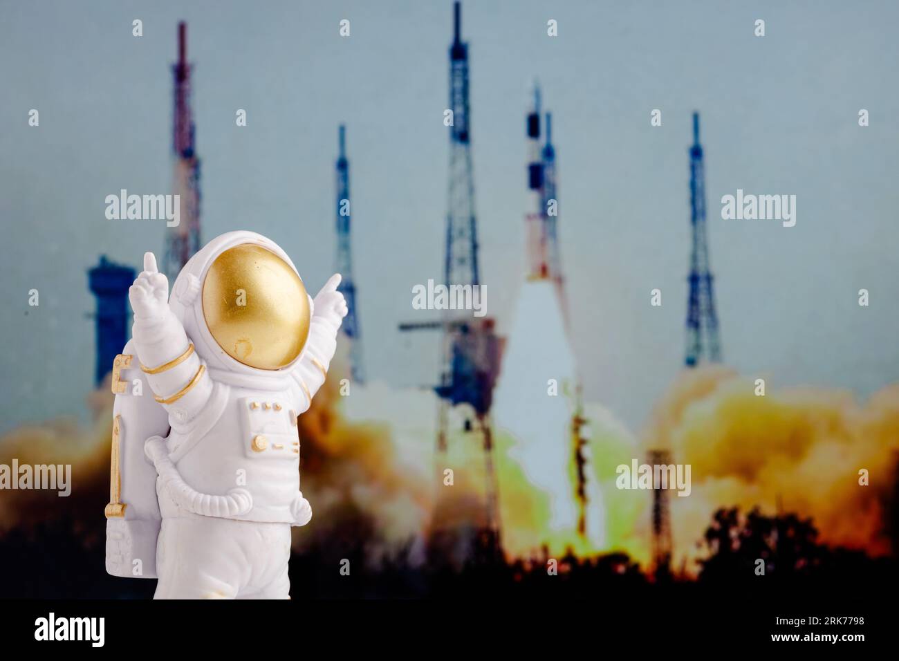 A toy astronaut figure stands against a backdrop of a rocket taking off ...