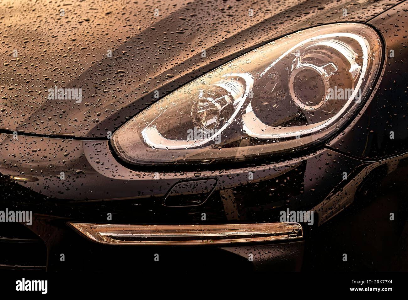 A striking close-up shot of a high-end luxury car's front headlight ...