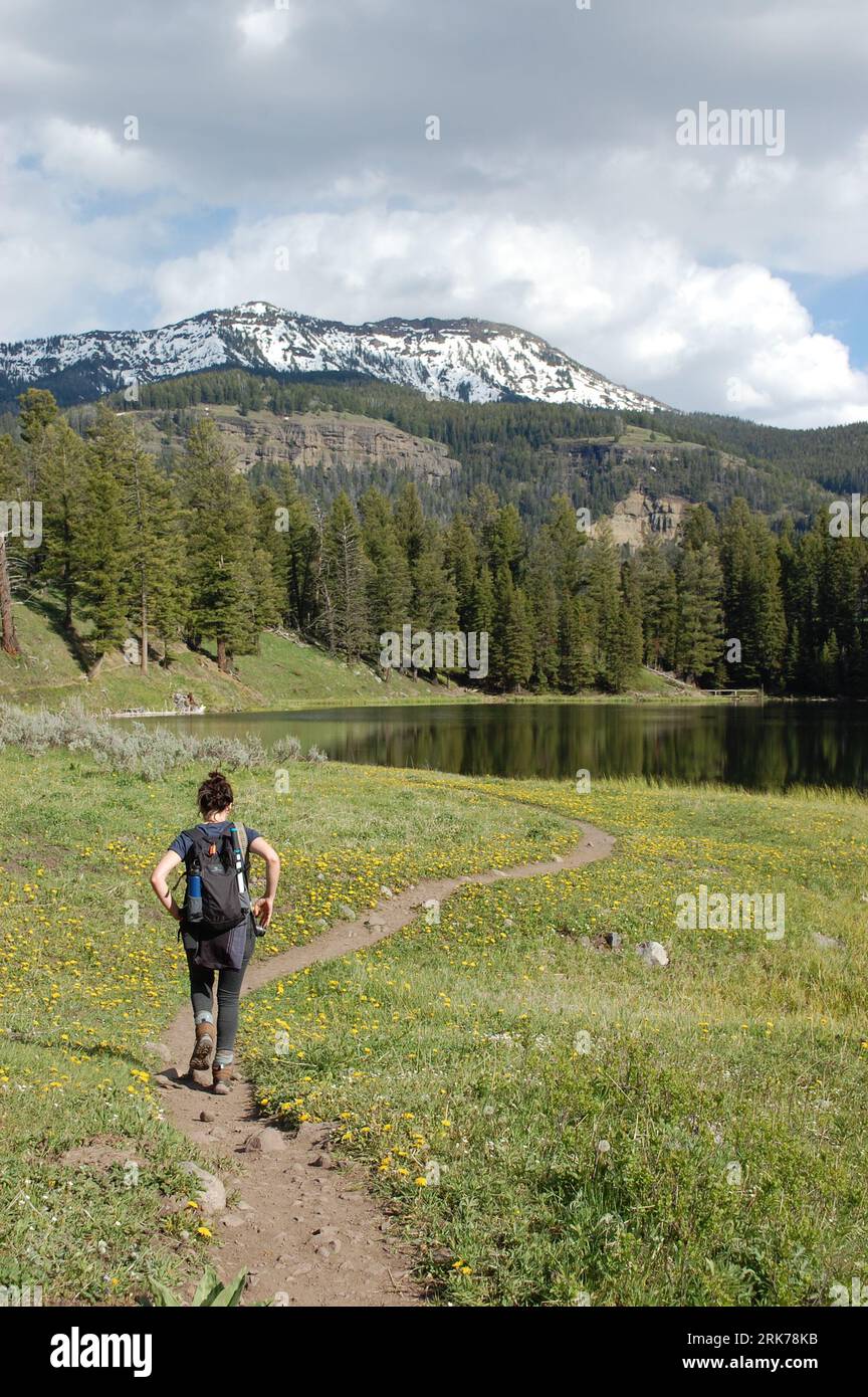 A middle-aged woman striding along a winding path leading to a tranquil ...