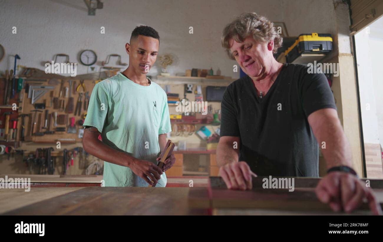 Master Carpenter Guiding Apprentice on Wood Sawing in Workshop, Young ...