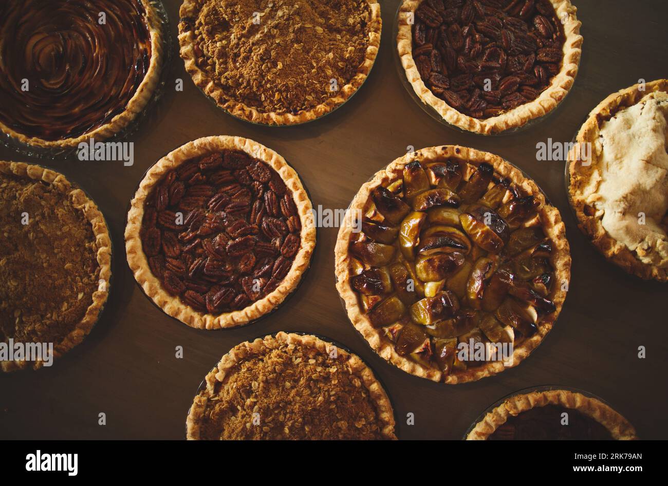 A variety of freshly made pies lined up on a kitchen table in a ...