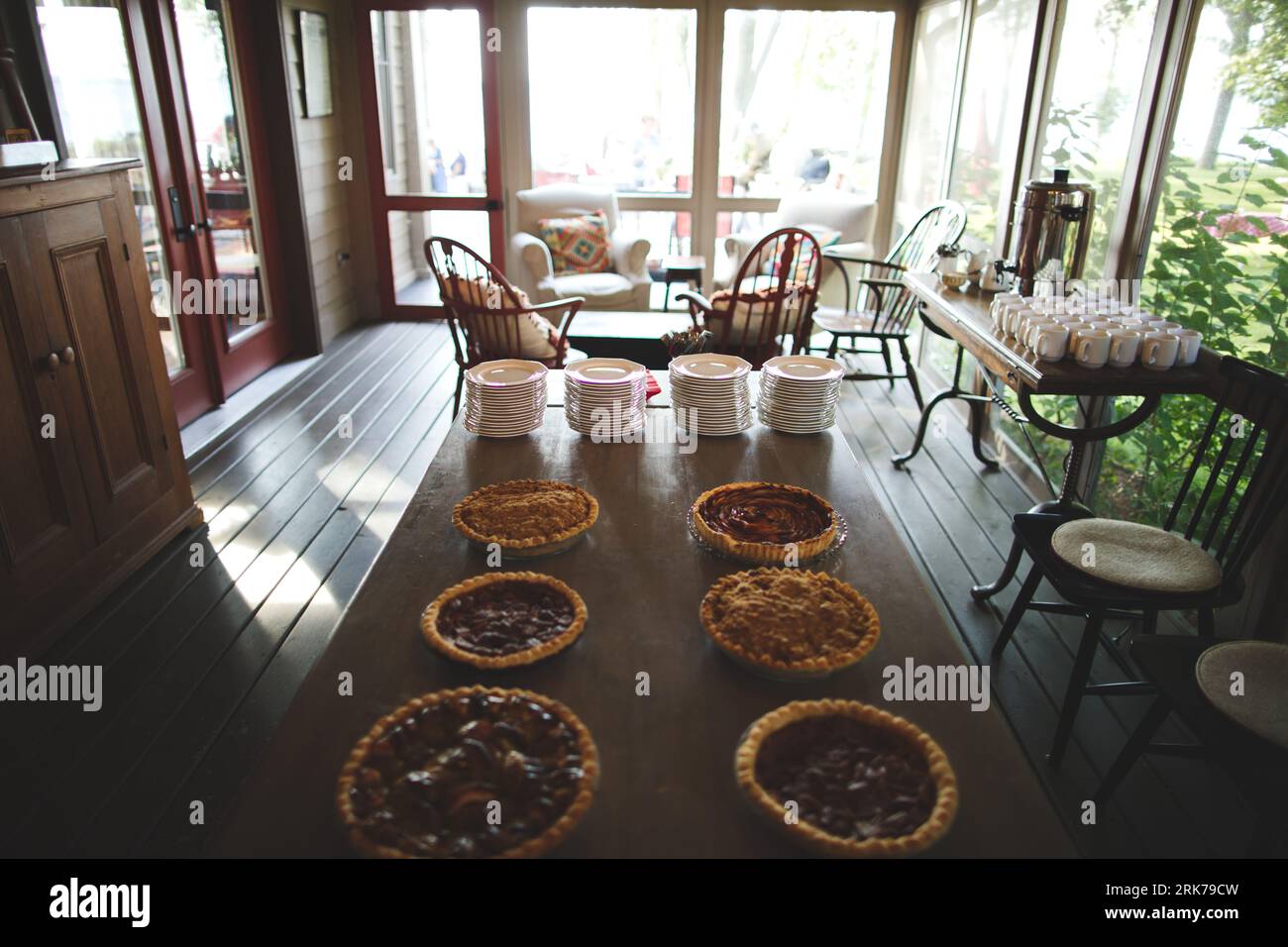 A variety of freshly made pies lined up on a kitchen table in a ...