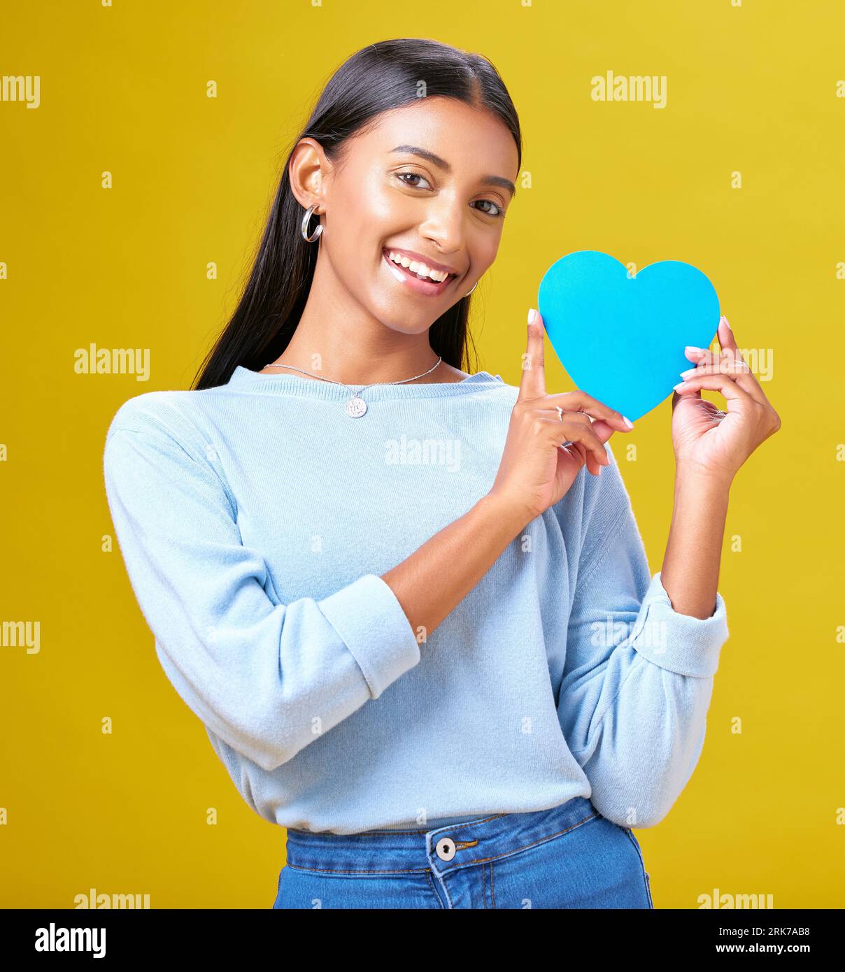 Portrait, donation and woman with blue heart in studio for help, hope ...