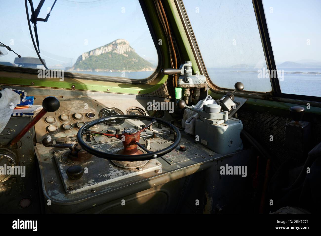 A close-up of a steering wheel on a large boat, overlooking a serene ...